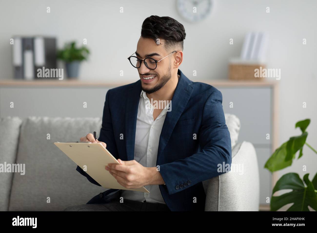 Positive arab male psychologist writing in clipboard, having session ...