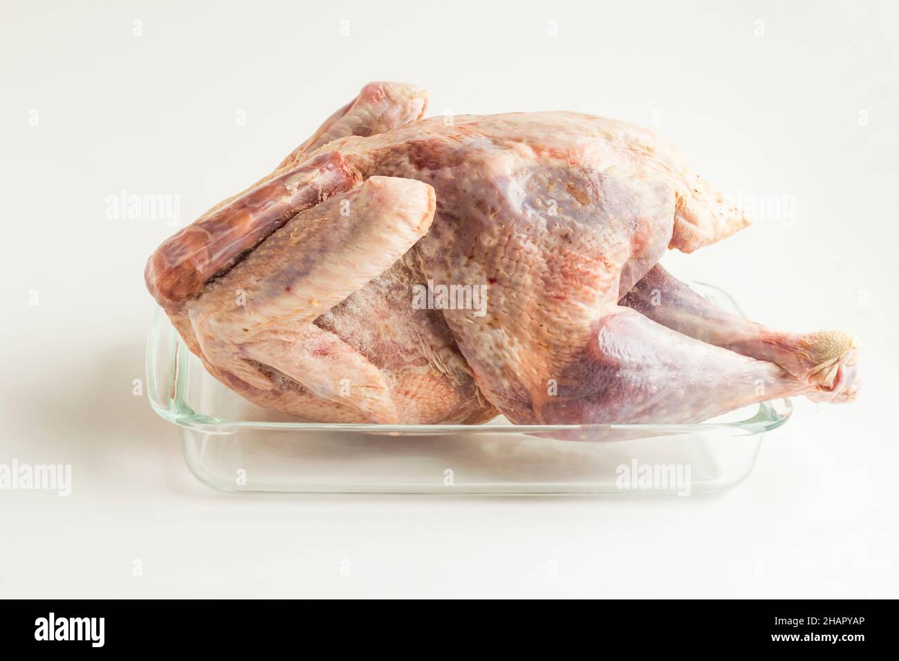 Frozen,uncooked turkey in the glass oven container on the white surface ...