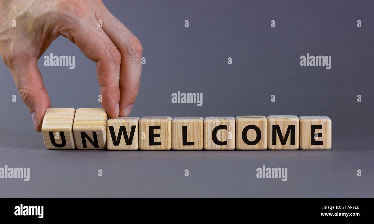 Welcome or unwelcome symbol. Businessman turns wooden cubes and changes ...
