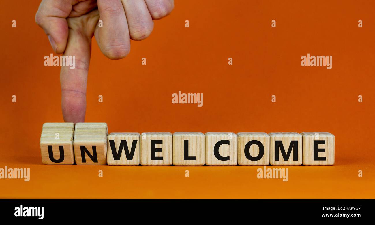Welcome or unwelcome symbol. Businessman turns wooden cubes and changes ...
