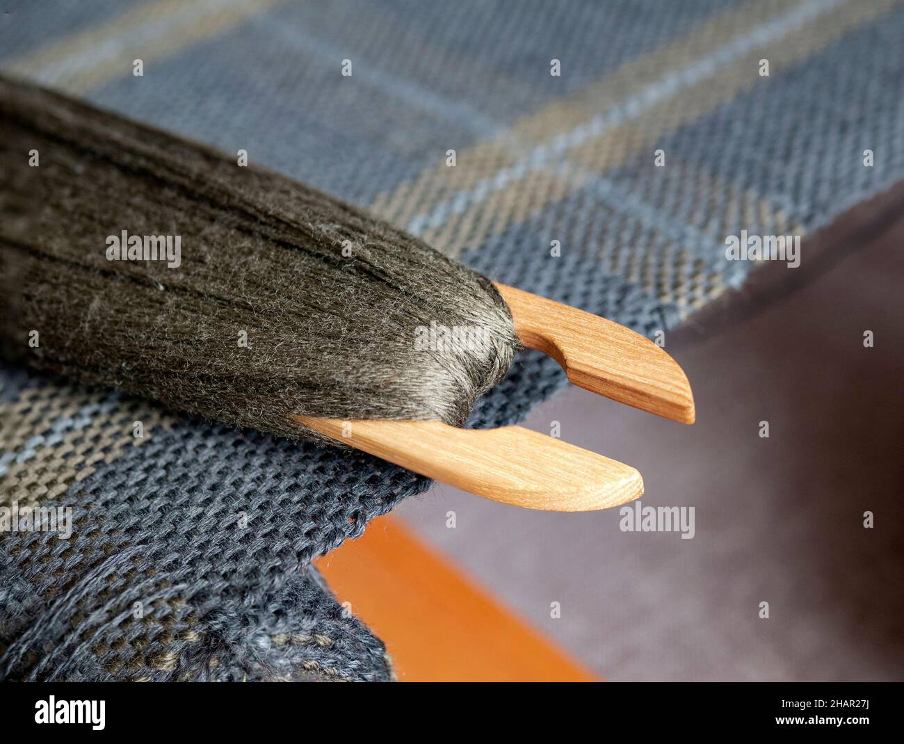 Shuttle with dark thread on the hand woven fabric, close up. Handloom ...