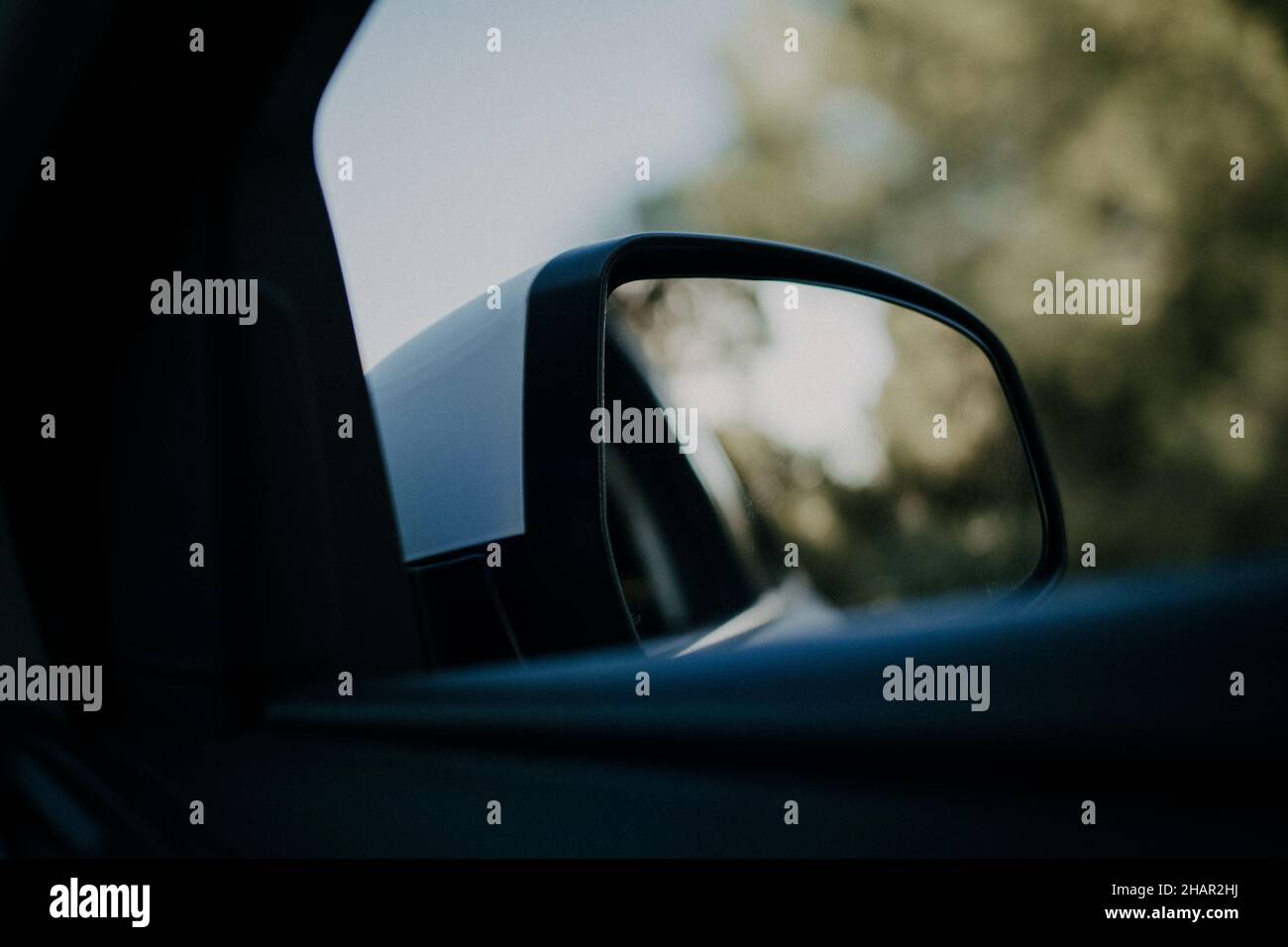 Close-up shot of a side mirror of a car reflecting nature in daylight ...