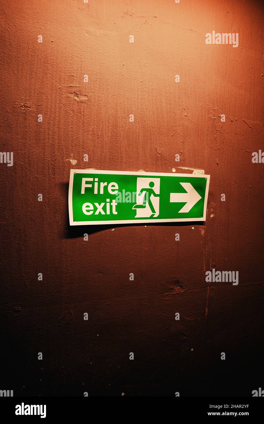 Fire Exit sign on a dark red wall Stock Photo - Alamy