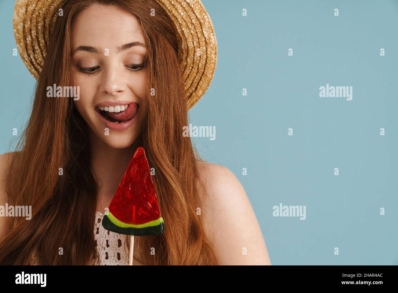 Young ginger woman showing her tongue while posing with lollipop ...