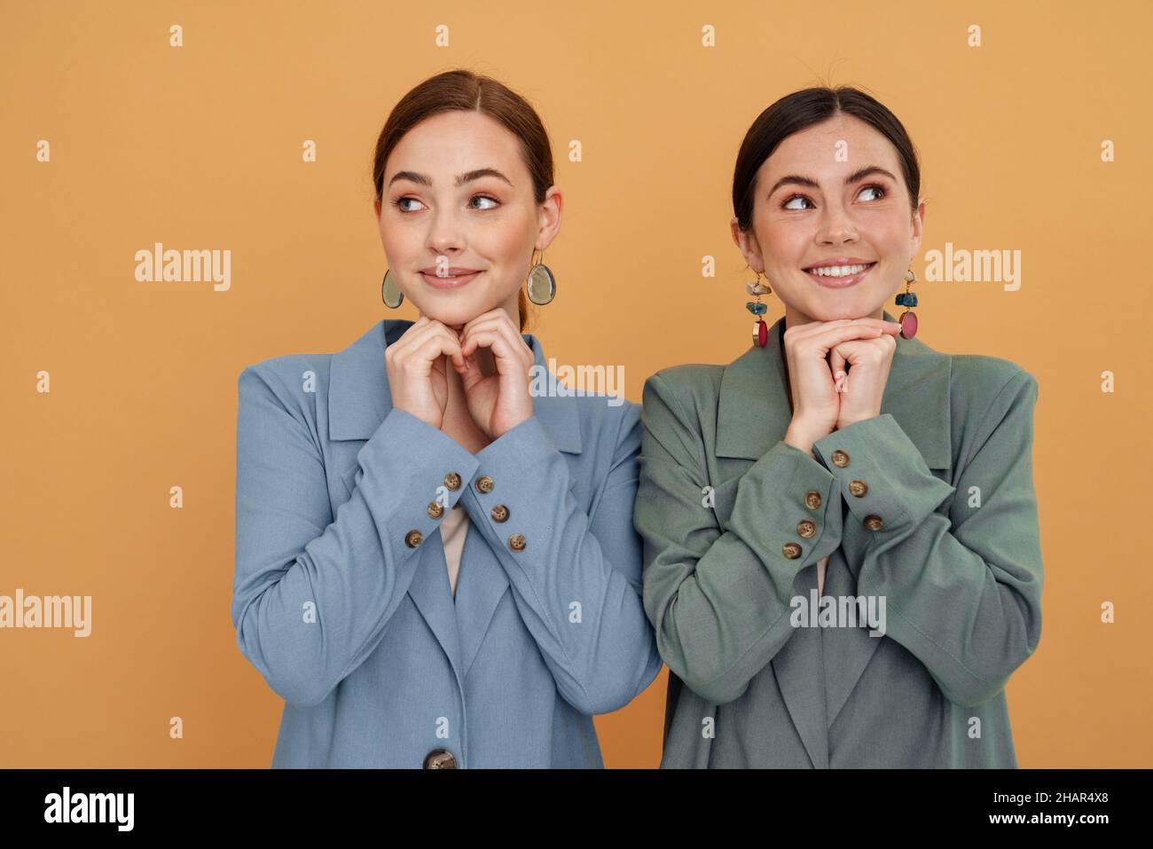 Young two women wearing jackets smiling and looking at opposite sides ...