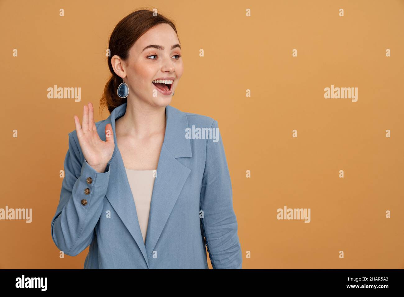 Young ginger woman in jacket laughing and waving hand isolated over ...