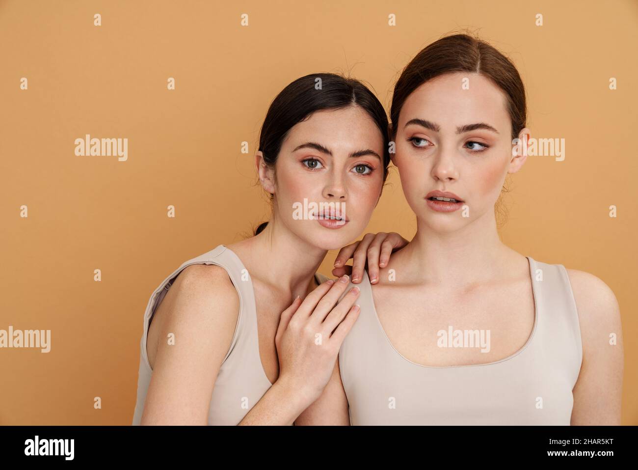 Young two women in undershirt hugging and posing at camera isolated ...