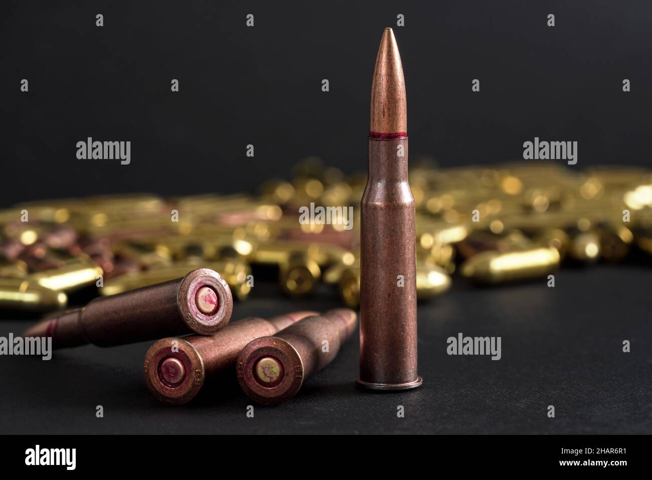 Copper machine gun bullets, more blurred yellow ammo on black board ...