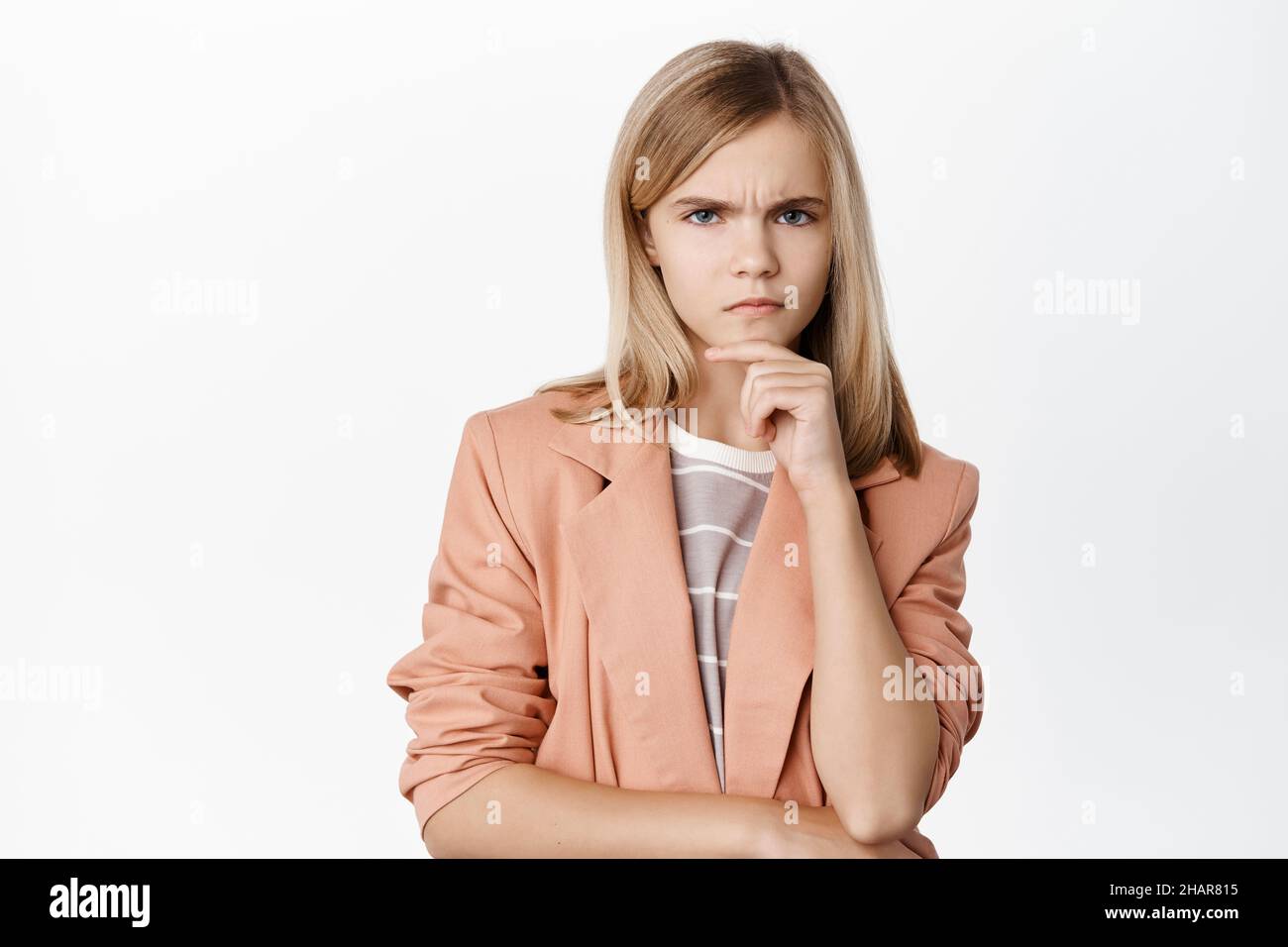 Cute blond girl in blazer, looking thoughtful and complicated, frowning ...