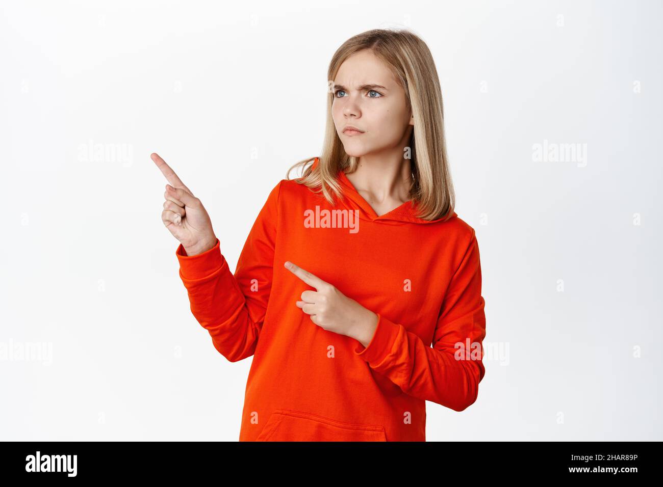 Sulking little girl staring at upper left corner, pointing at logo ...