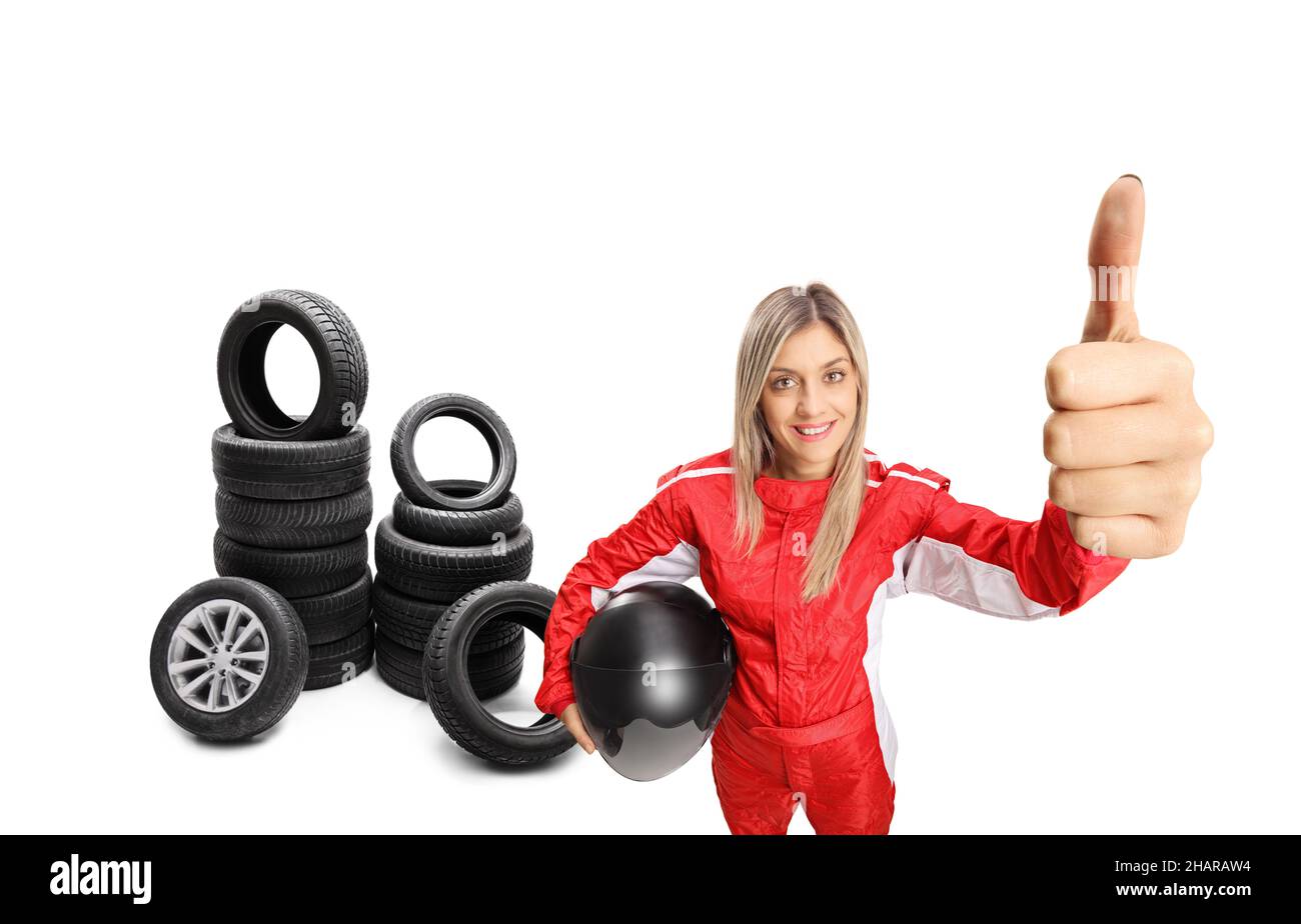 Female racer making a thumb up sign in front of car tires isolated on ...