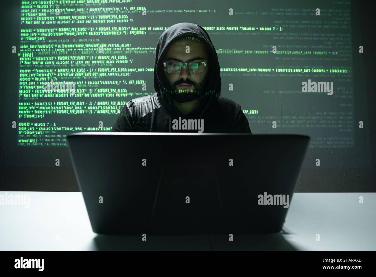 Hispanic man in front of his laptop with green coding behind him on a ...