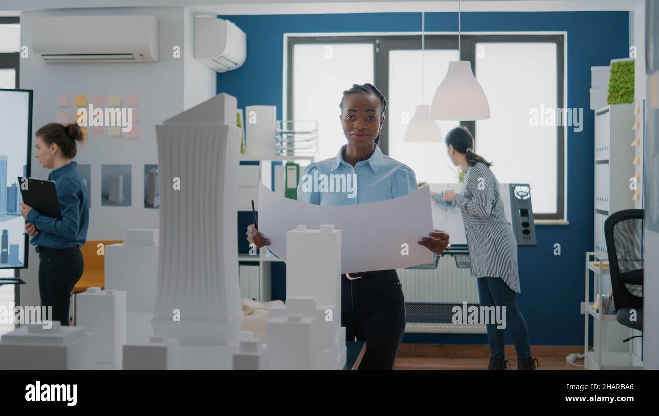 Portrait Of Woman Architect Analyzing Blueprints Plans On Paper To Design Building Model And
