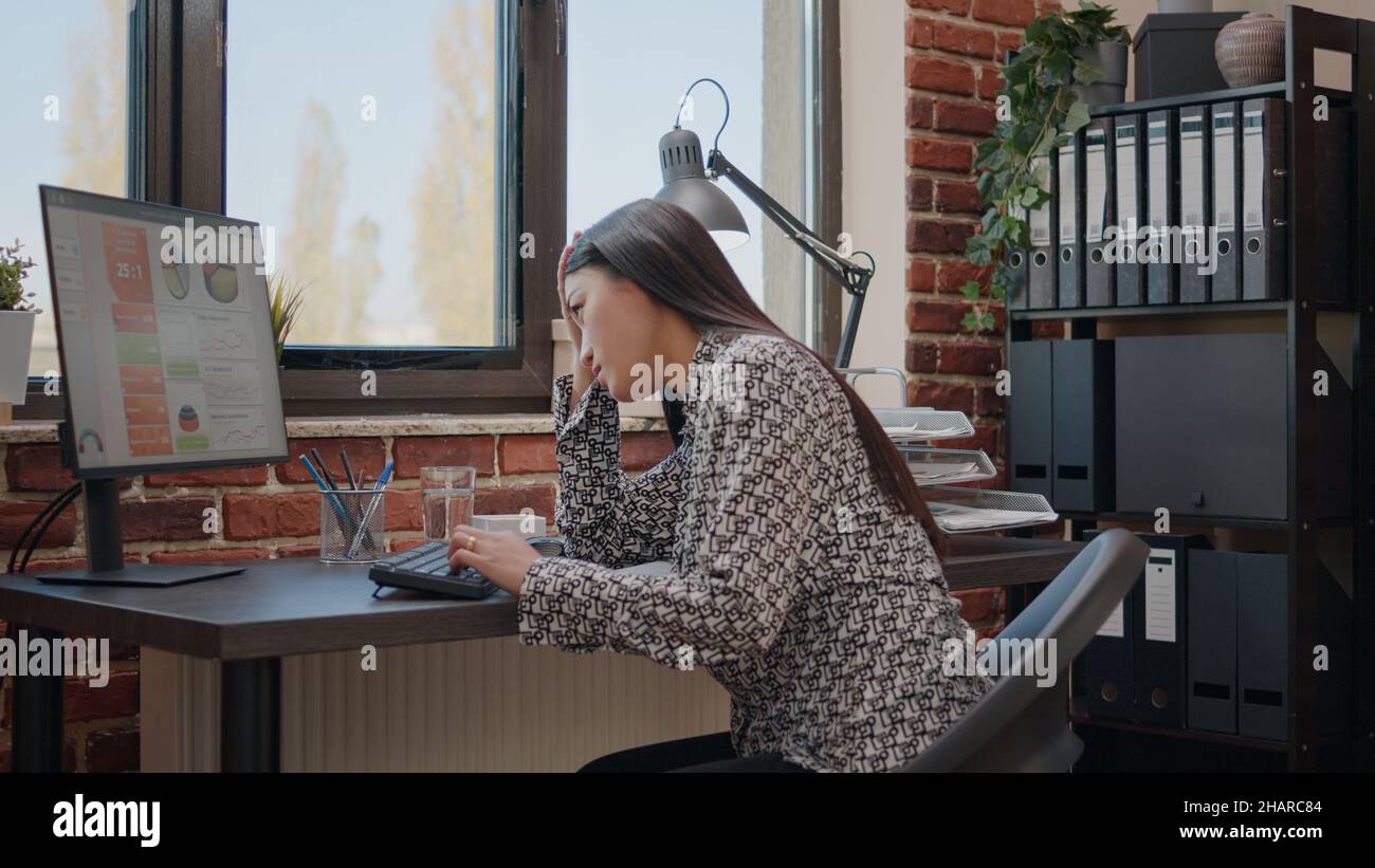 Employee dealing with headache while she works on project in startup ...