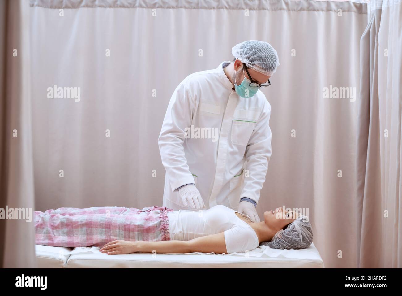 Young Caucasian male doctor in white uniform and with sterile mask on ...