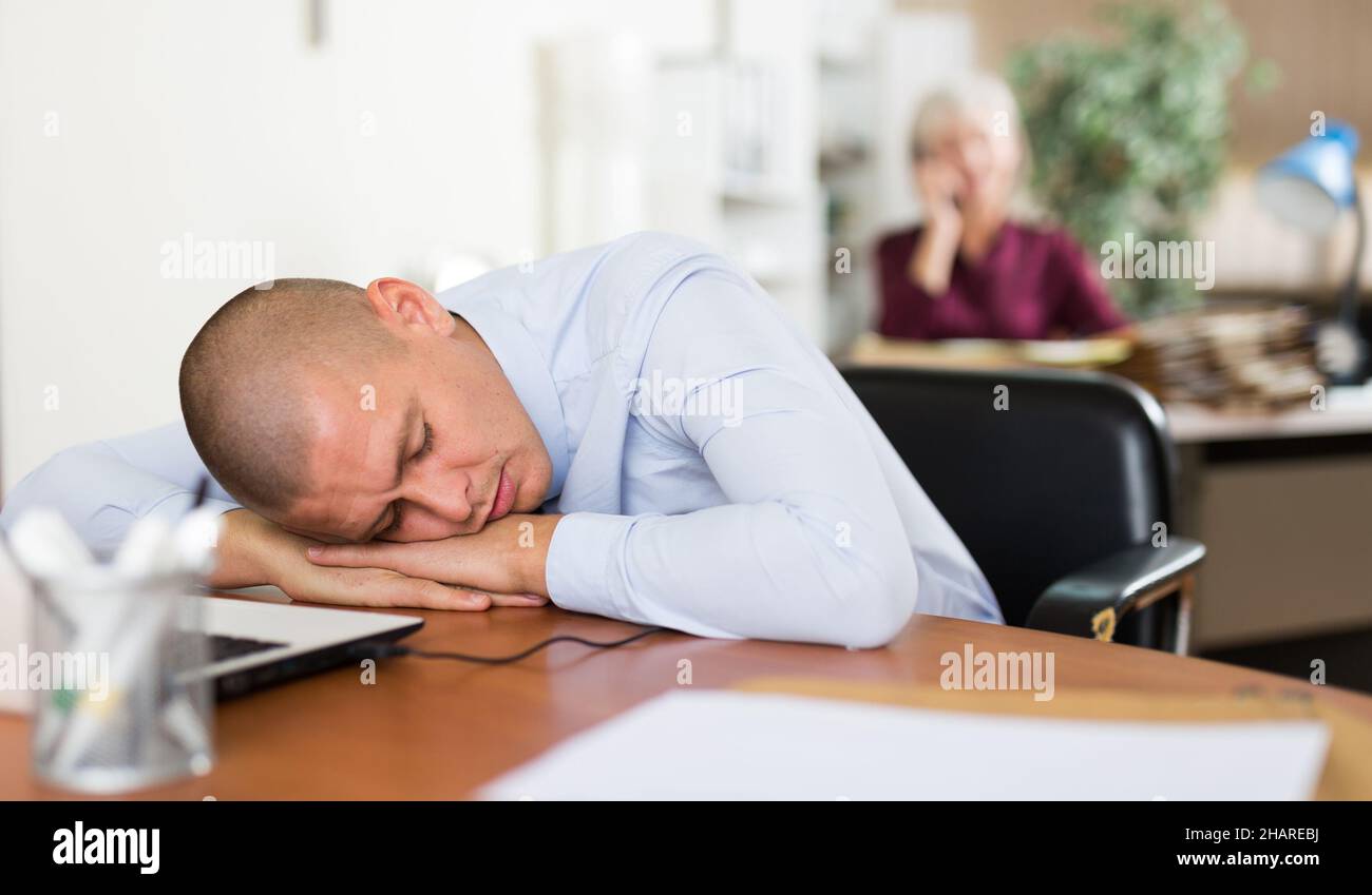 Exhausted businessman sleeping on table resting his head on hands Stock ...