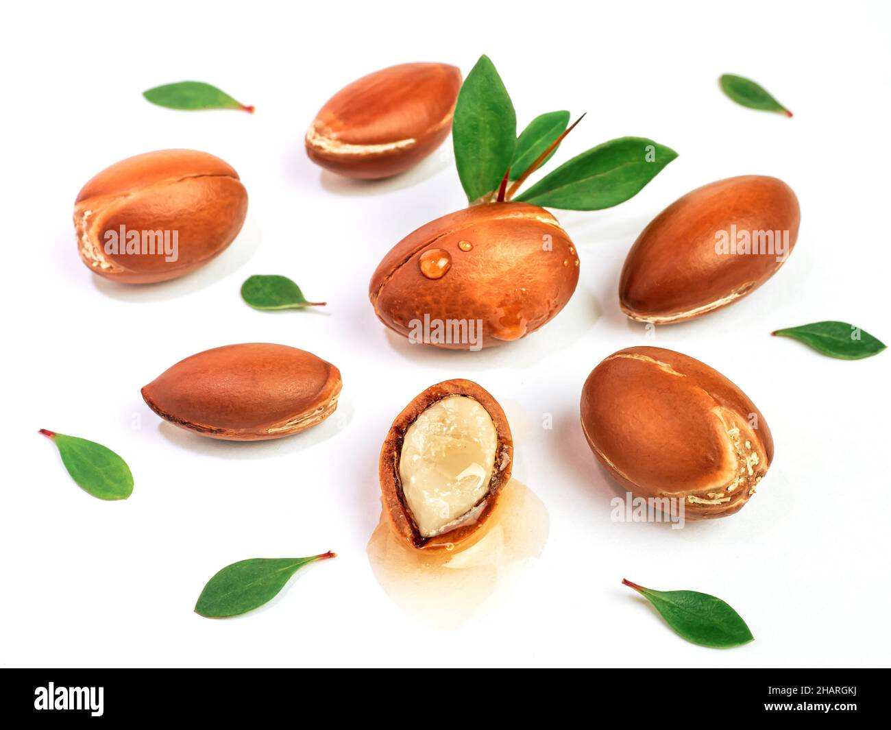 Argan nuts with green leaves on an isolated white background. Chopped ...