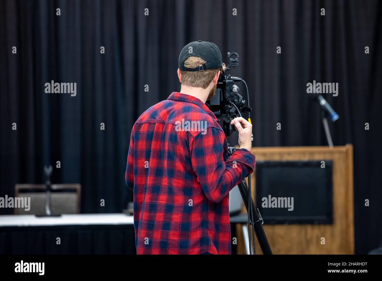 Rear view of the operator with camera preparing to record the meeting ...