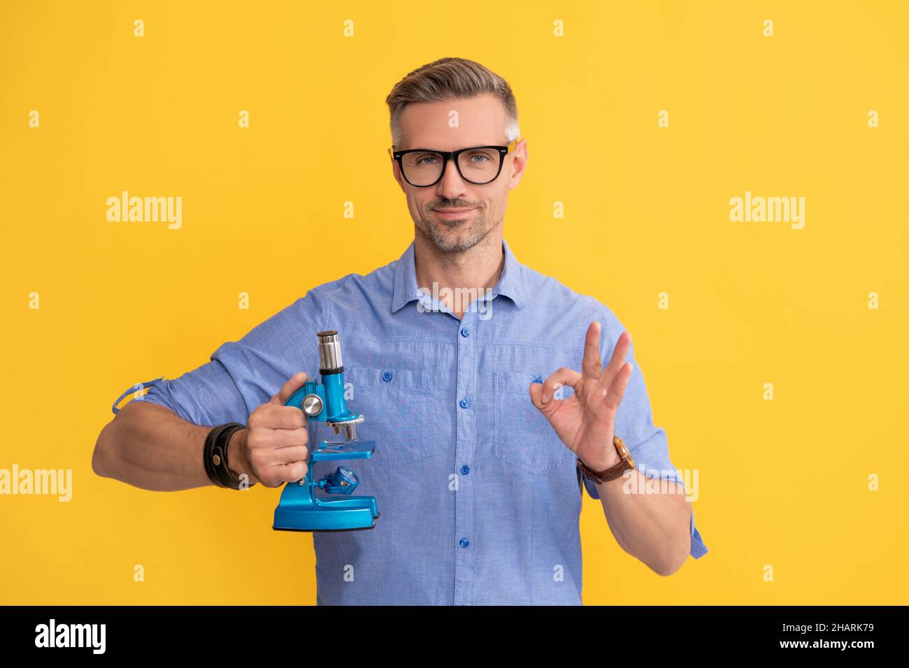 smiling scientist man in glasses hold microscope show ok gesture on ... smiling scientist man in glasses hold microscope show ok gesture on ...
