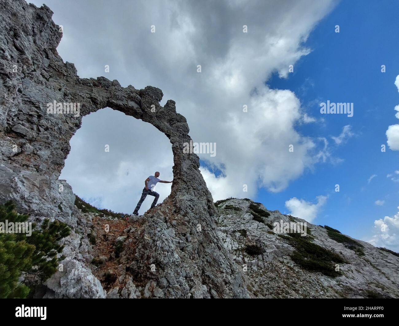 Tourist standing under an arched stone formation Stock Photo - Alamy
