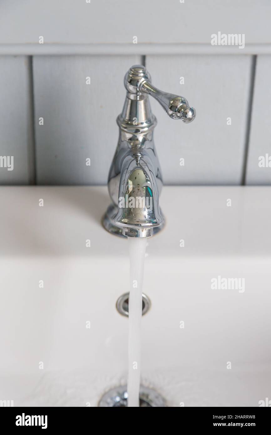 Water running from an open water faucet with white sink background ...