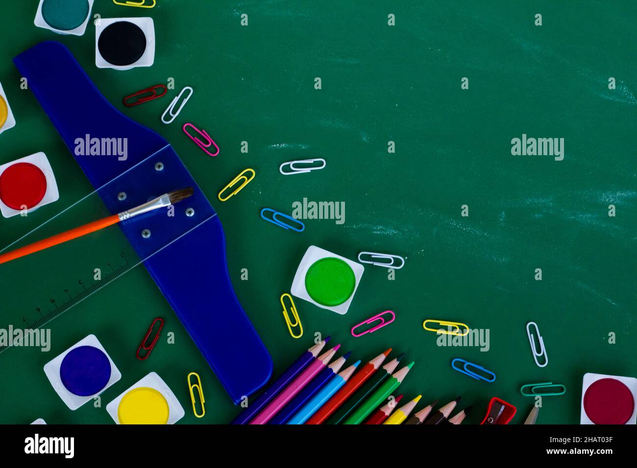 Colorful school supplies on greenboard with chalk dust trail and copy ...