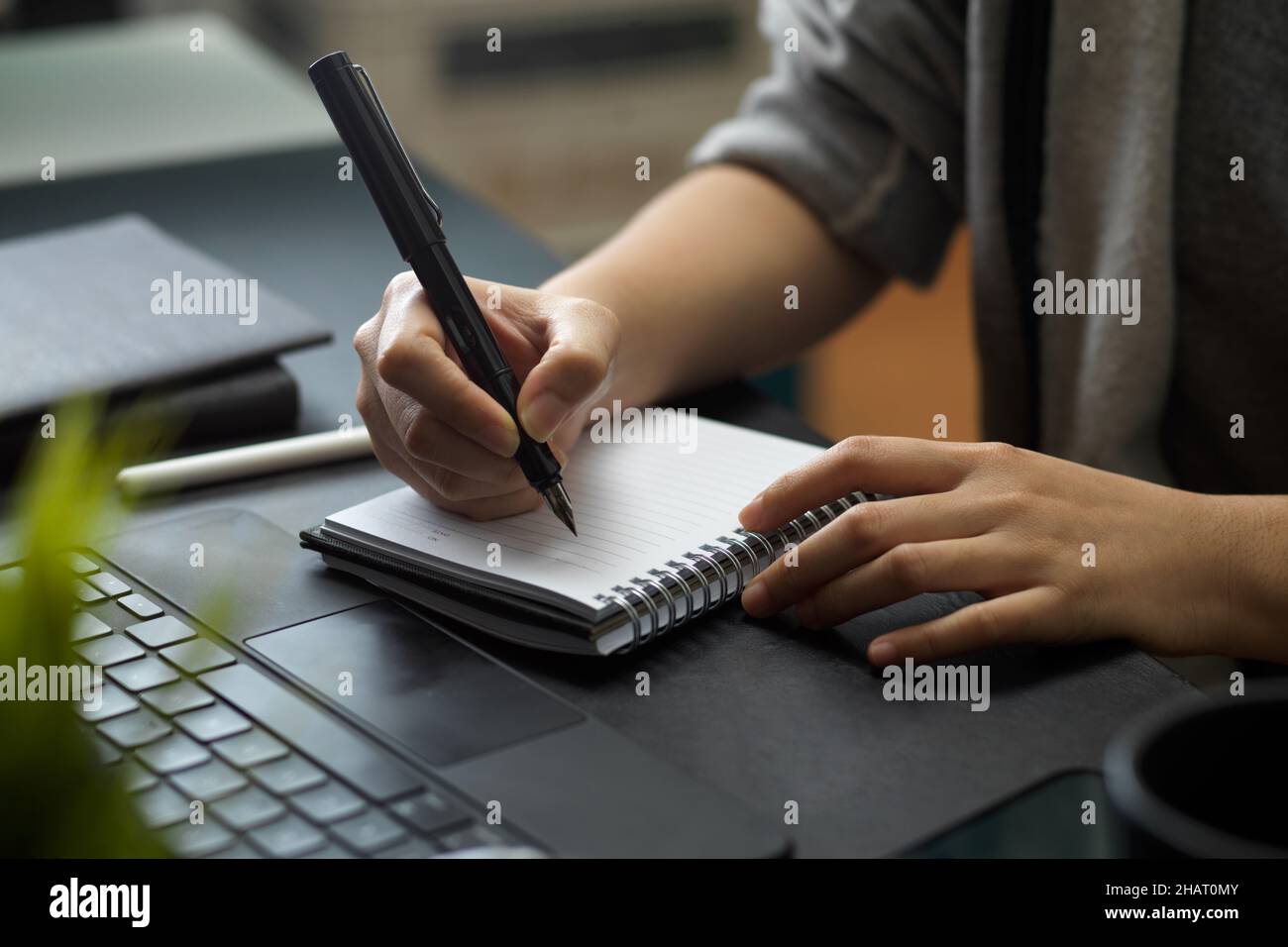 A female pay attention on taking notes on notepad at her office desk ...