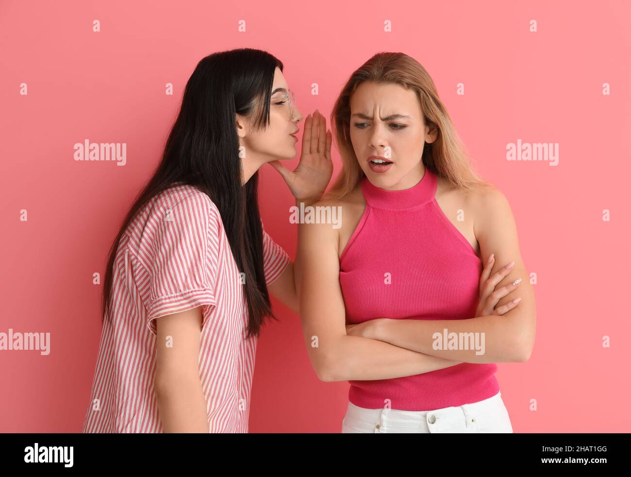 Young gossiping women on color background Stock Photo - Alamy