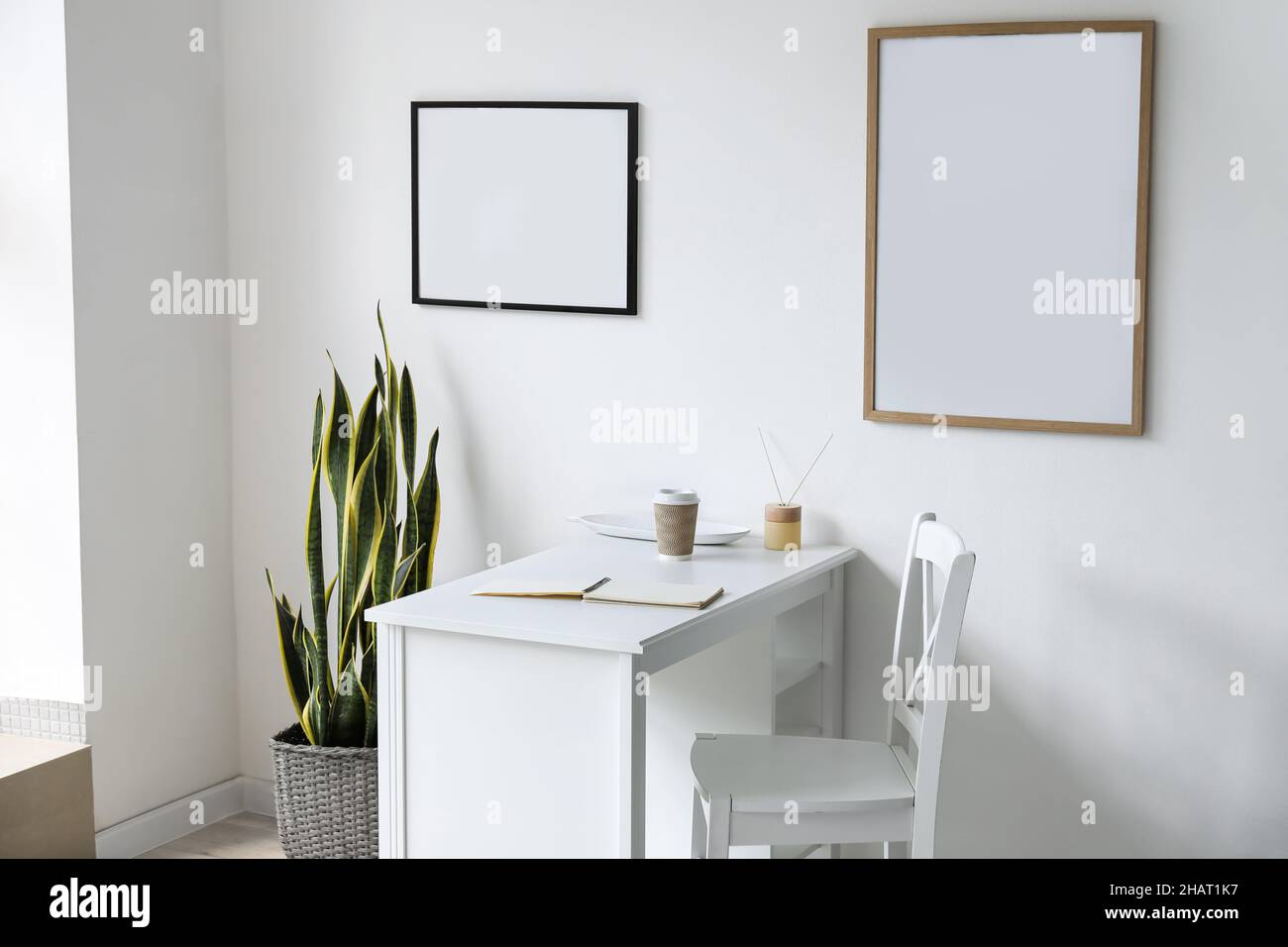 Modern workplace and blank frames hanging on light wall Stock Photo - Alamy