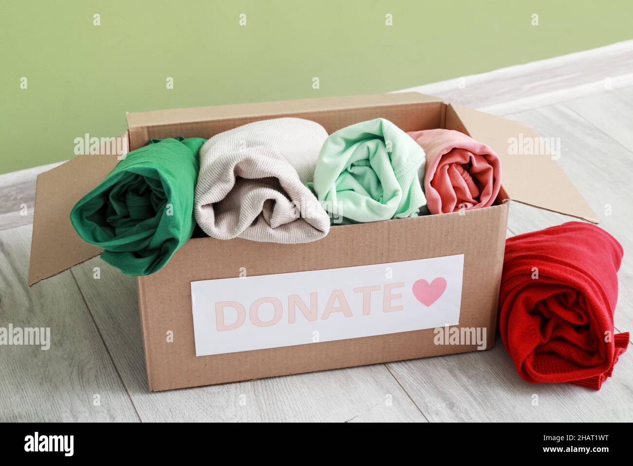 Cardboard box with donation clothes near green wall Stock Photo - Alamy