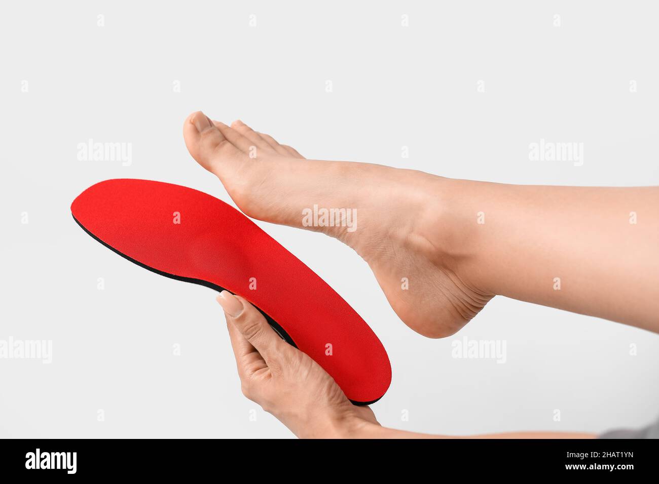 Woman fitting red orthopedic insole on light background Stock Photo - Alamy