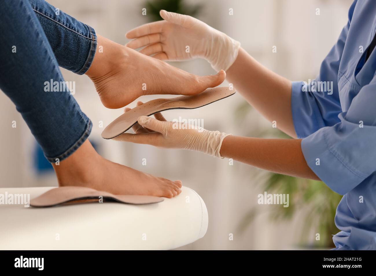 Female orthopedist fitting beige insole on patient's foot in clinic ...
