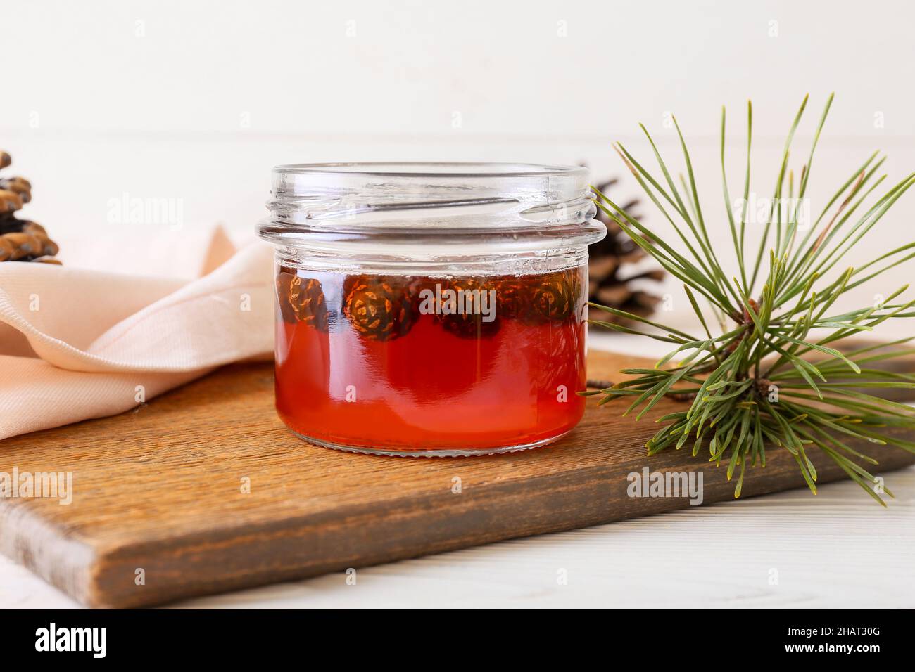 Jar of tasty pine cone jam and fir tree branch on light background ...