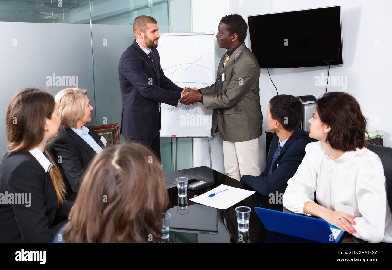 Two businessman shaking hands in meeting room, confirming successful ...