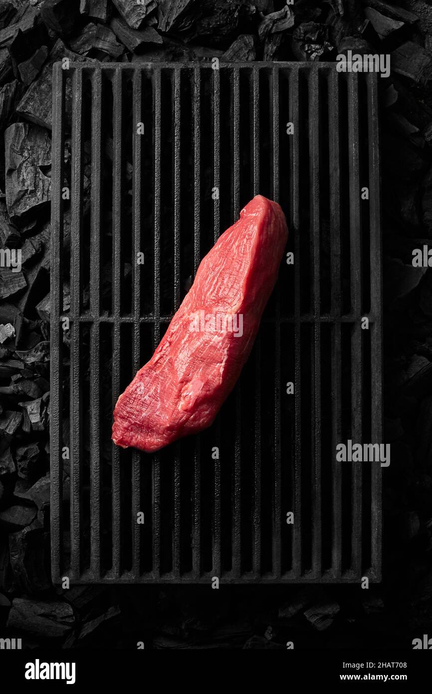 Piece of lean pork tenderloin on black cast iron grill grate over cold ...