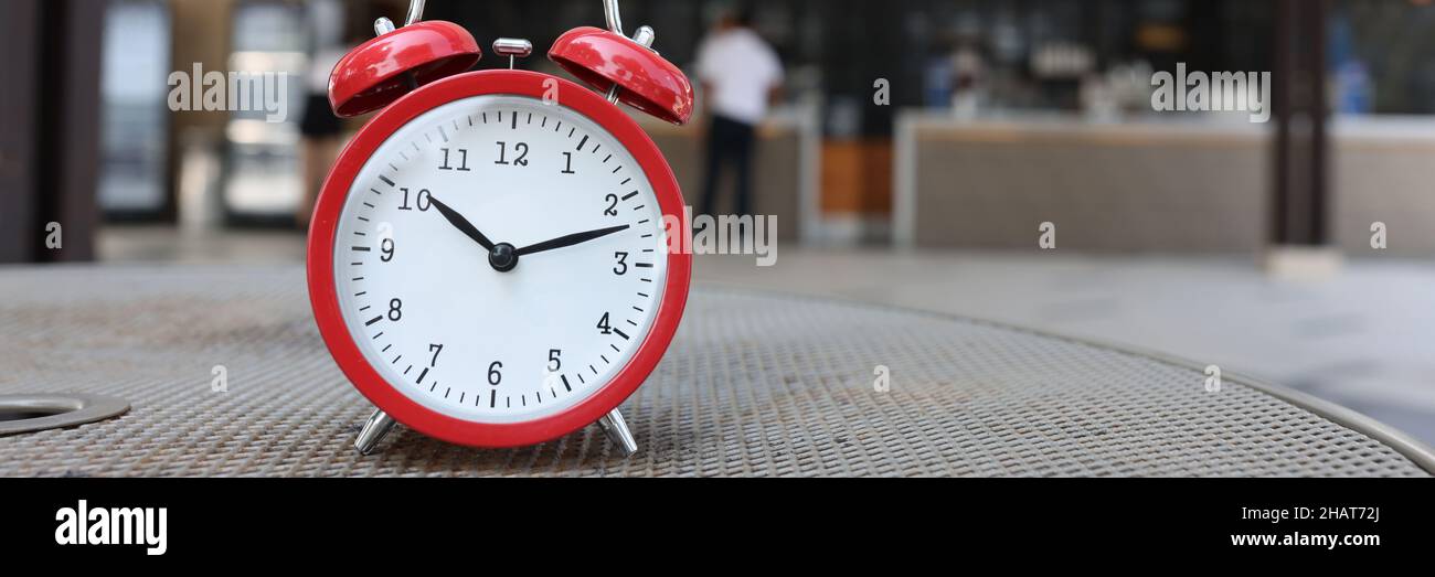 Red alarm clock showing time of ten in morning on background of ...