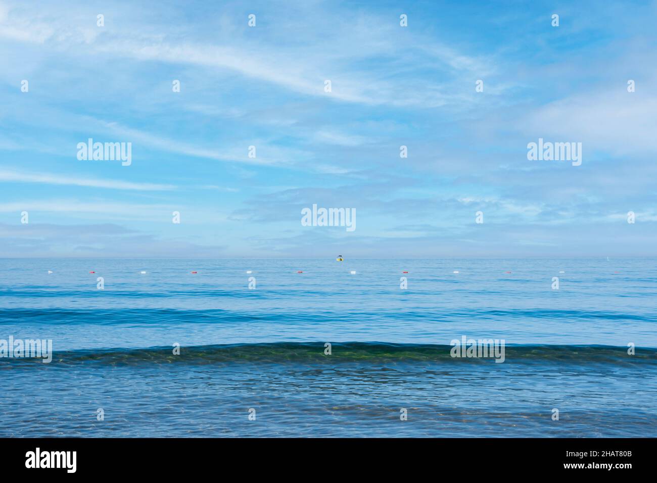 Smooth sea surface, beach and cloudy sky. a small boat and signal ...