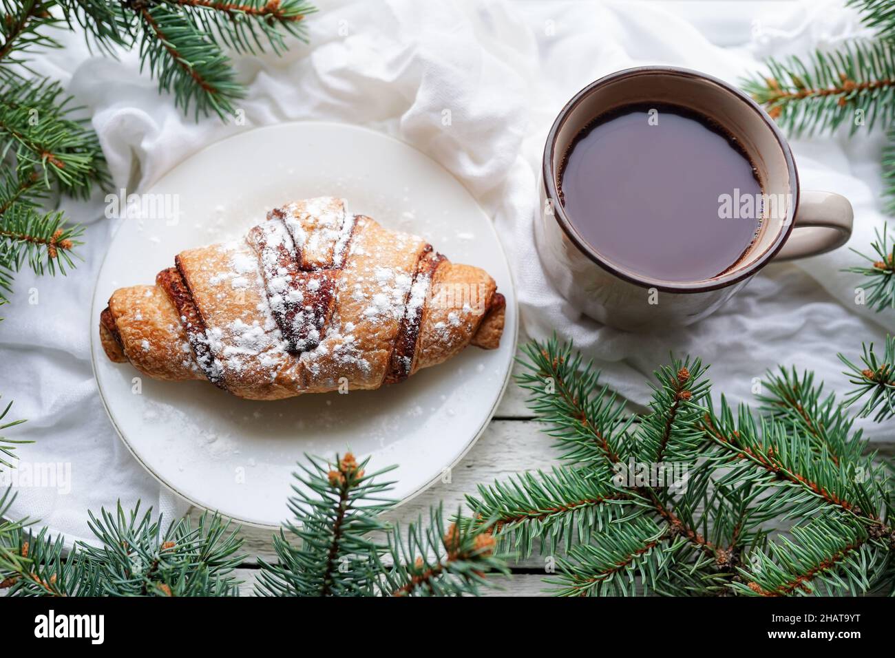 Christmas breakfast. Cup of coffee, croissant and tree fir branches on ...