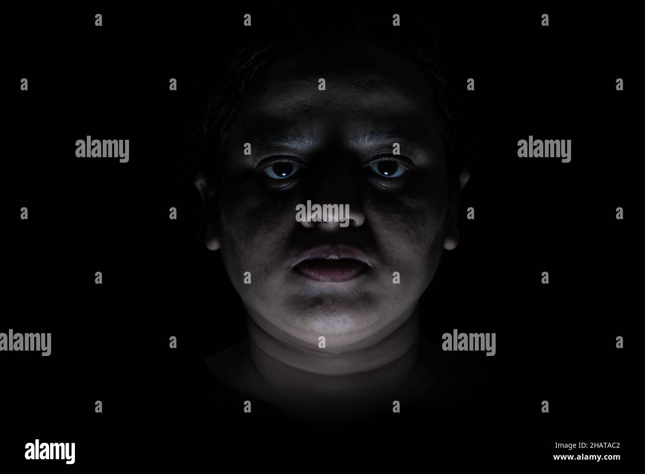 Spooky female face hiding in shadow with a creepy serious expression ...