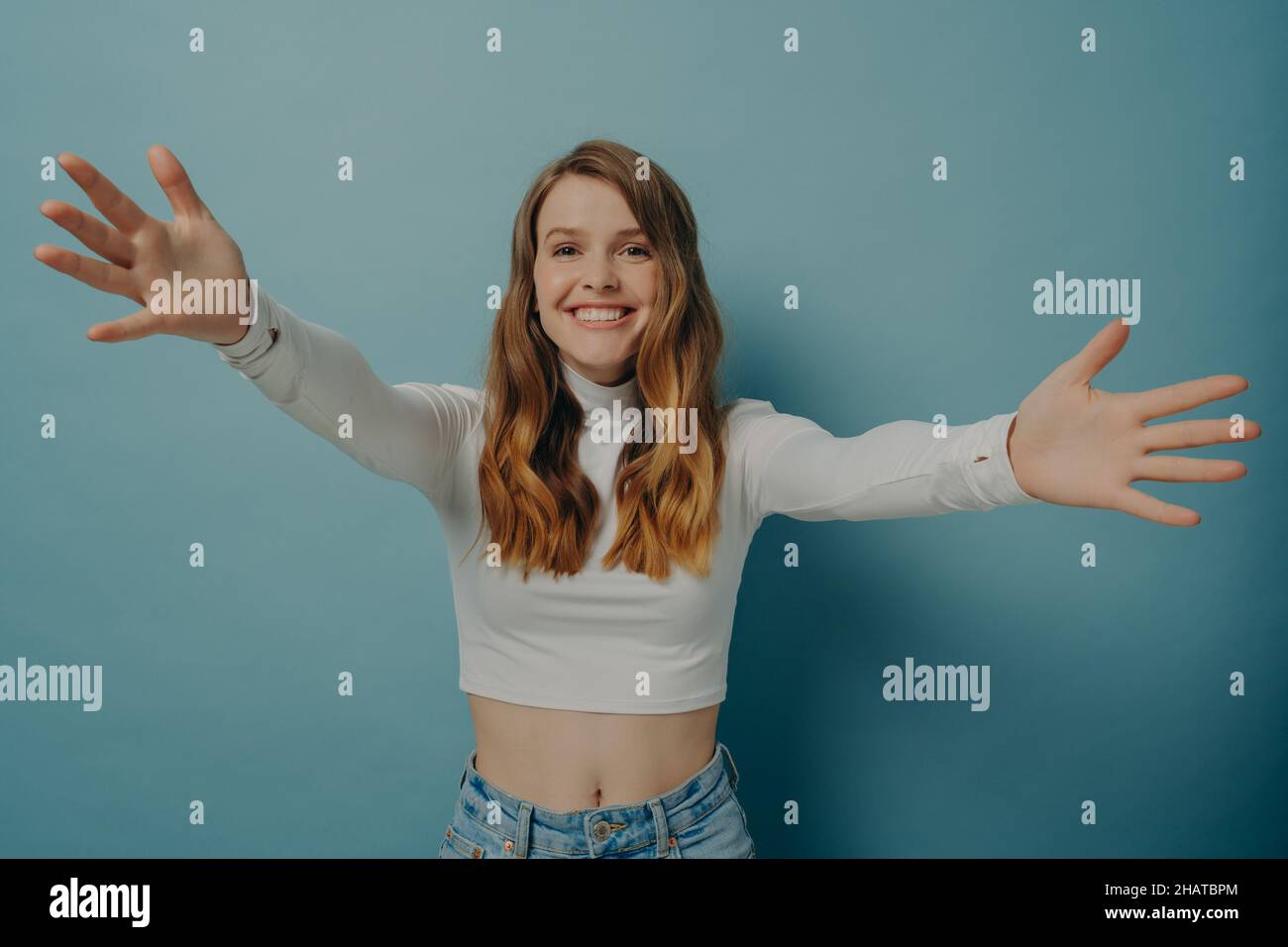 Overjoyed cheerful young woman with arms wide open outstretched to ...