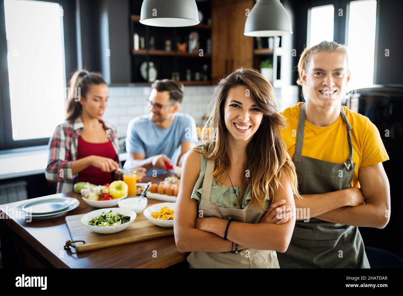 Group of happy friends laughing and talking while preparing meals in ...