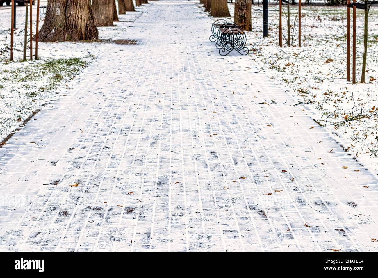 Paving paths in the park, covered with the first snow in winter. Winter ...