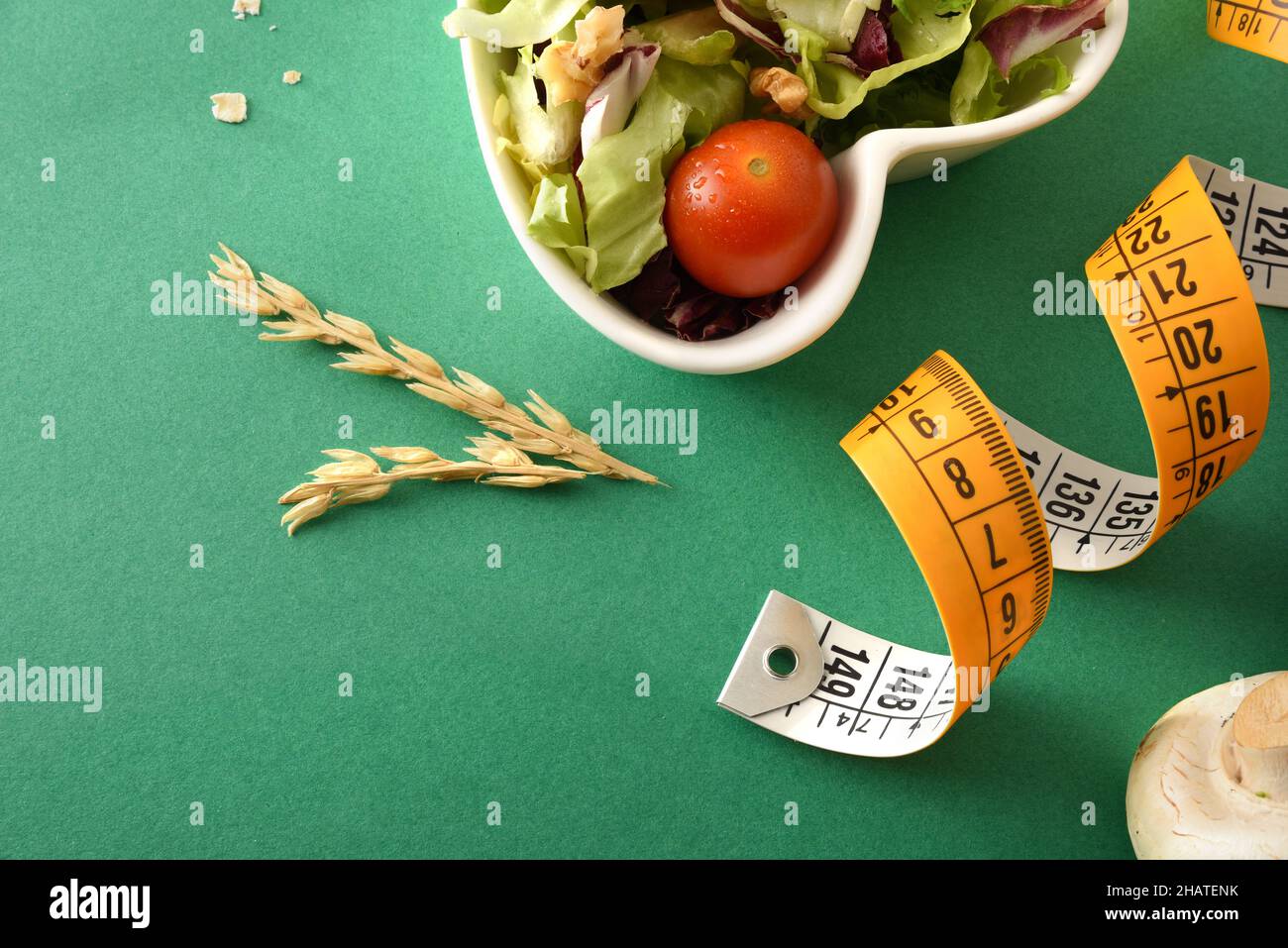 Concept of diet with meter and salad in container on green background ...