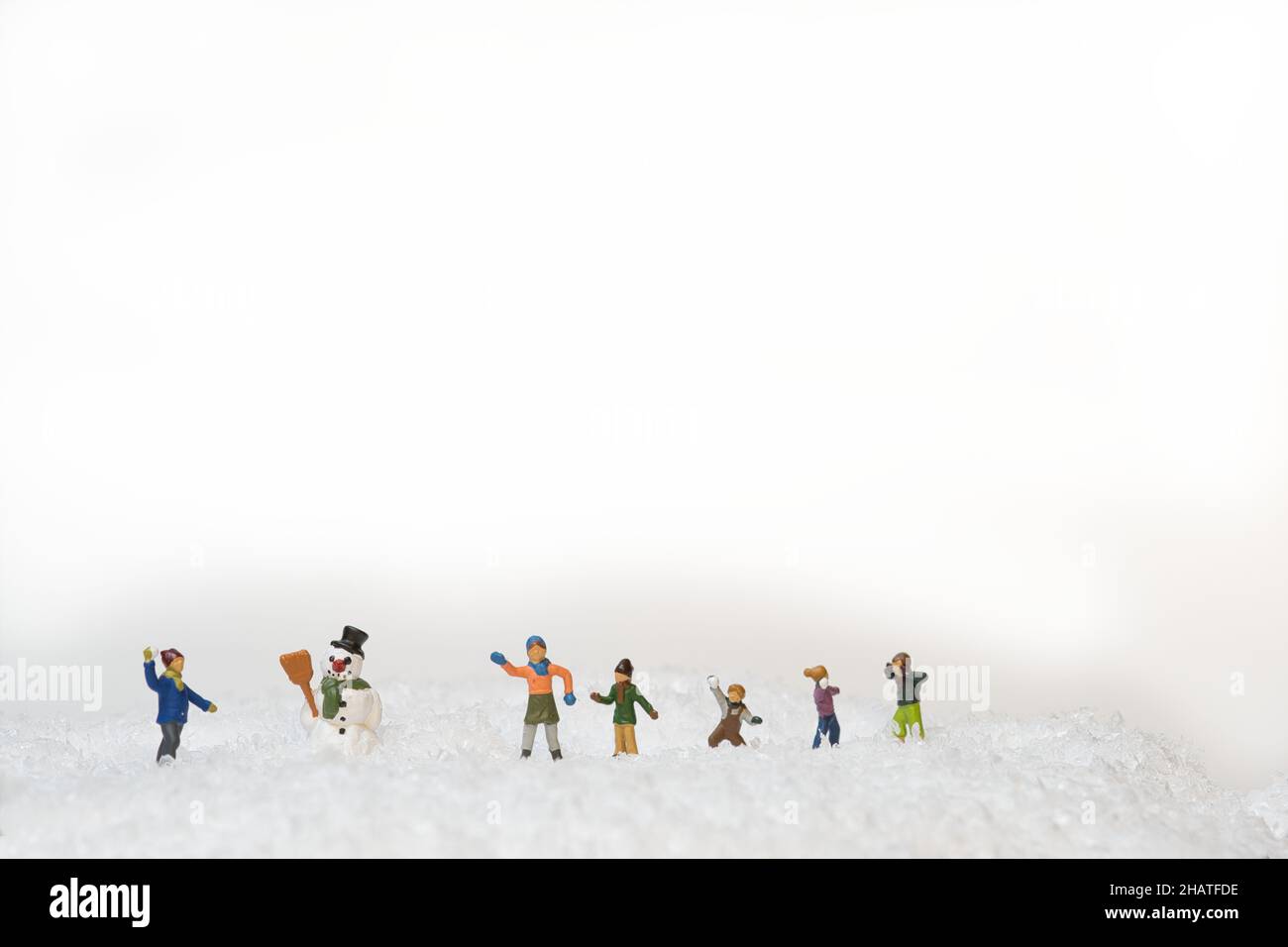 Group of miniature figures of kids throwing snowballs in snow around a ...