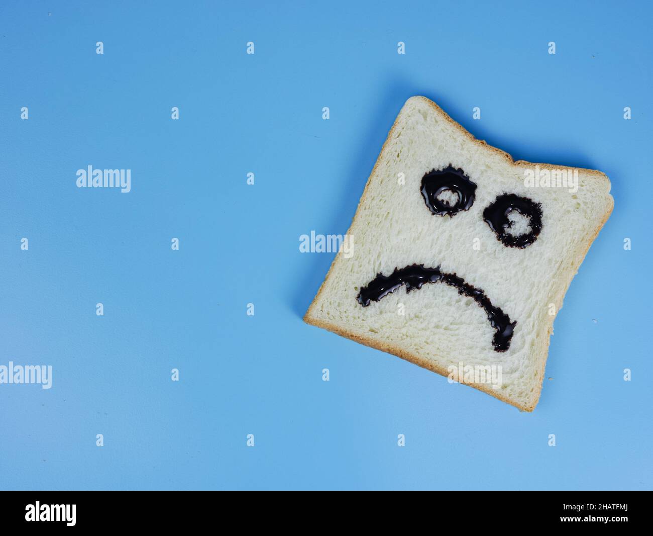 white bread with sad emoticon on blue pastel background Stock Photo - Alamy