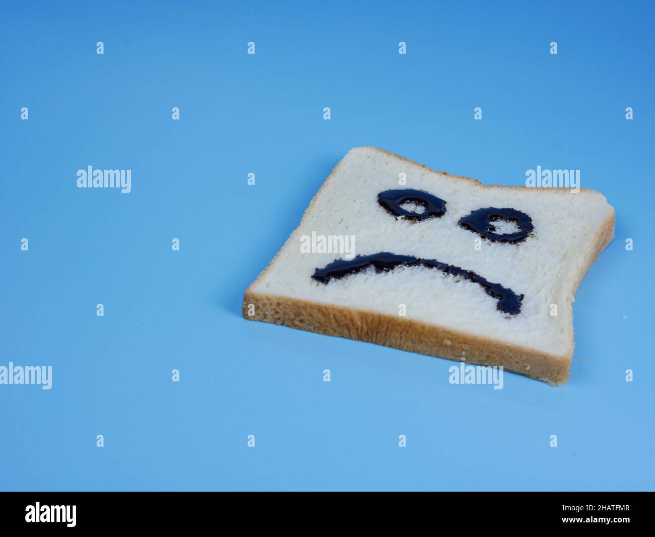 white bread with sad emoticon on blue pastel background Stock Photo - Alamy