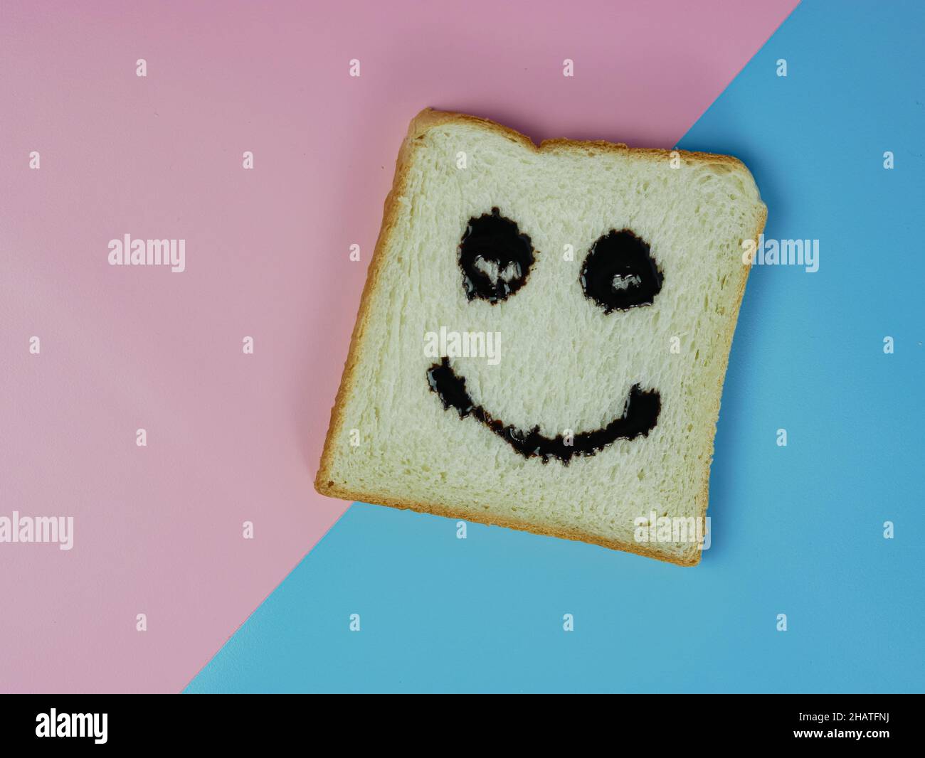 white bread with smiley emoticon on blue and pink pastel background ...