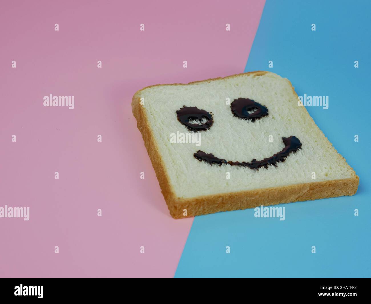 white bread with smiley emoticon on blue and pink pastel background ...