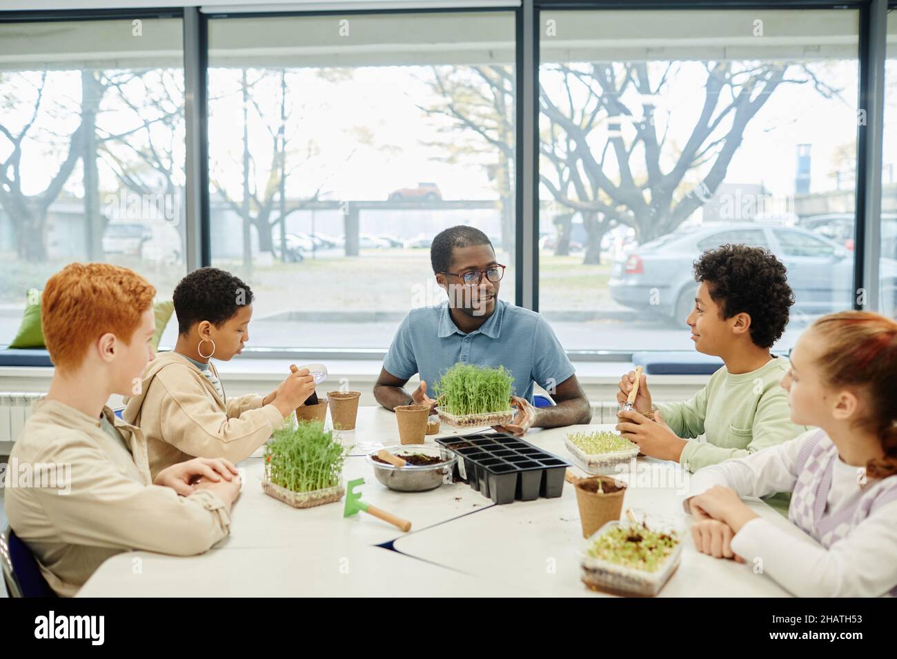 Diverse group of children planting seeds while experimenting at biology ...