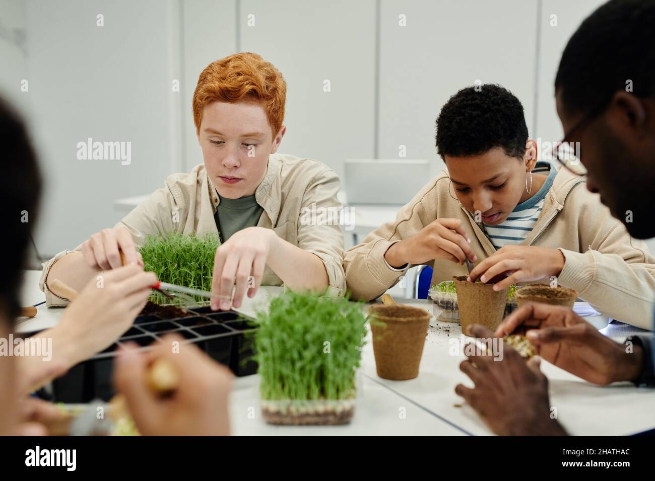 Diverse group of kids planting seeds while experimenting during biology ...